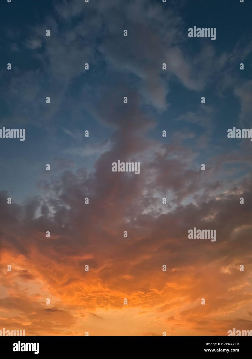 Beautiful sunset sky with colorful orange clouds over the horizon, vertical celestial background ...