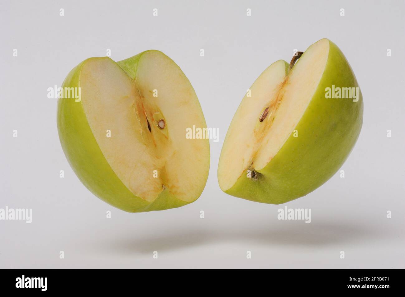 Green apple split in half on a white background, hovering Stock Photo ...
