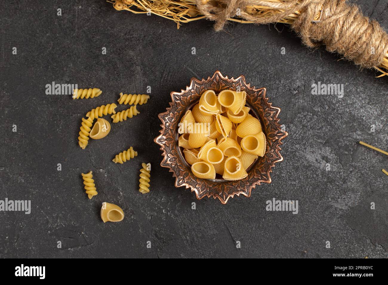 front view raw italian pasta little formed on the dark desk pasta ...