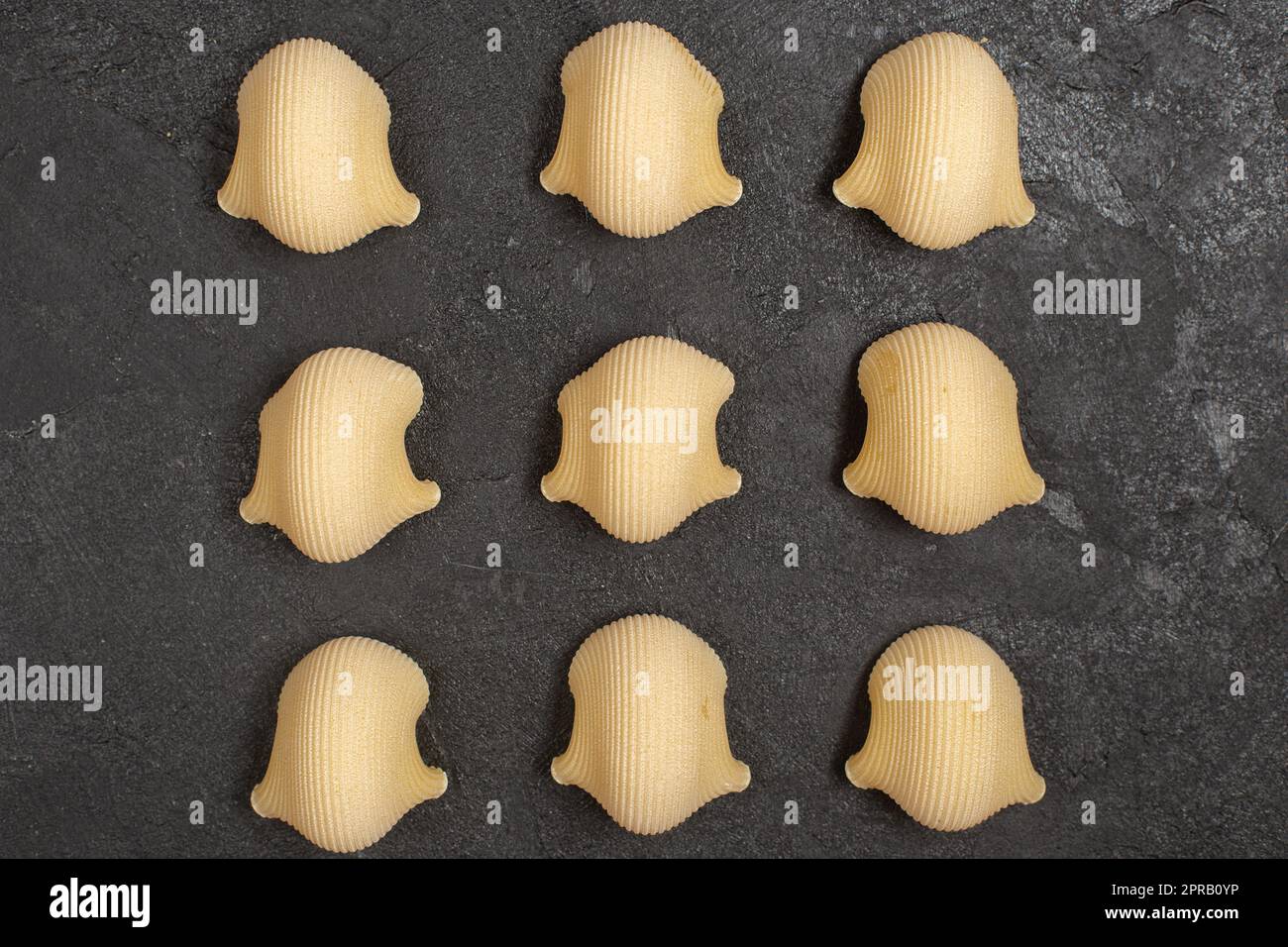 top view raw italian pasta little formed raw lined on the dark ...