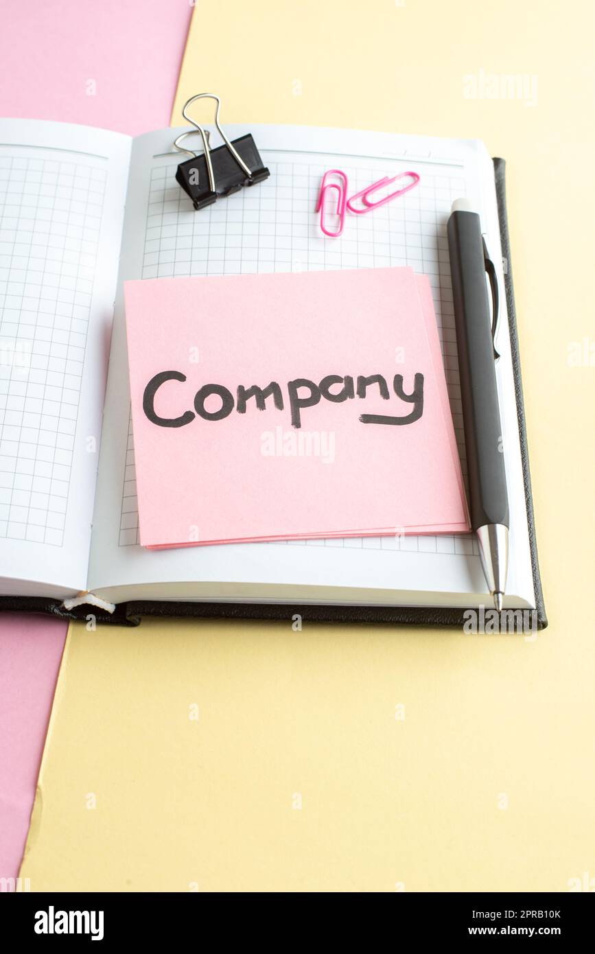 above view company written note on pink sticker with notepad yellow ...