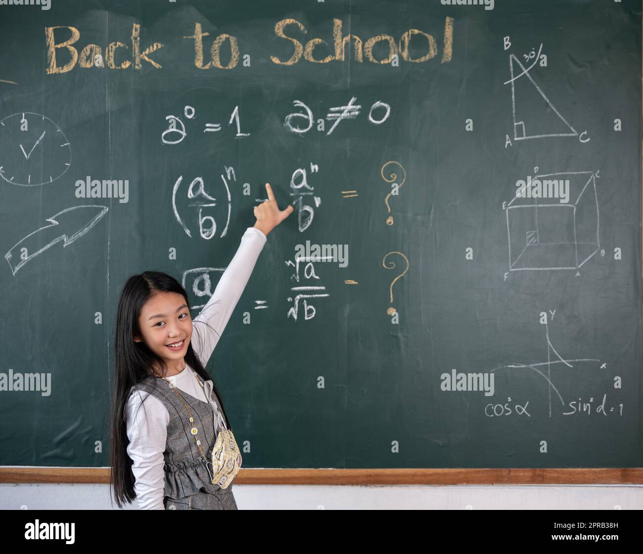 Asian school girl in uniform with backpack on classroom pointing up ...