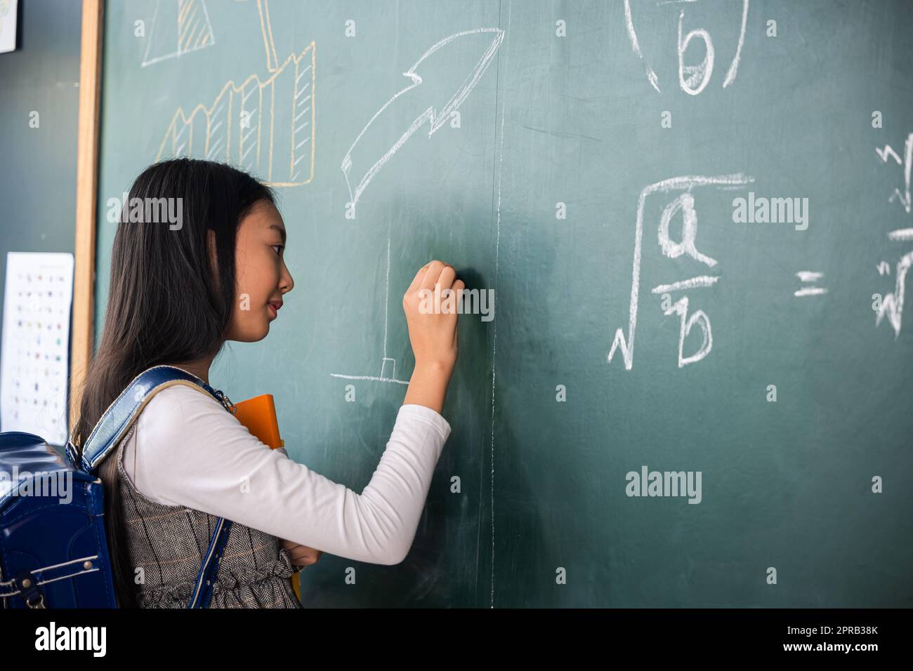 Back view of school girl on science lesson in classroom write an answer ...