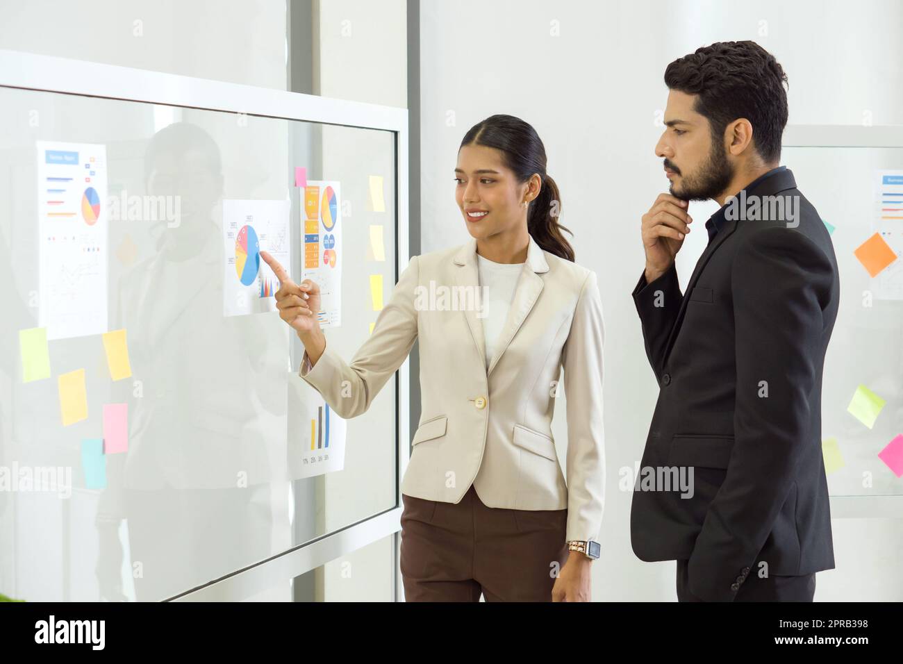 Young asian businesswoman in brown suit pointing finger at pie chart ...