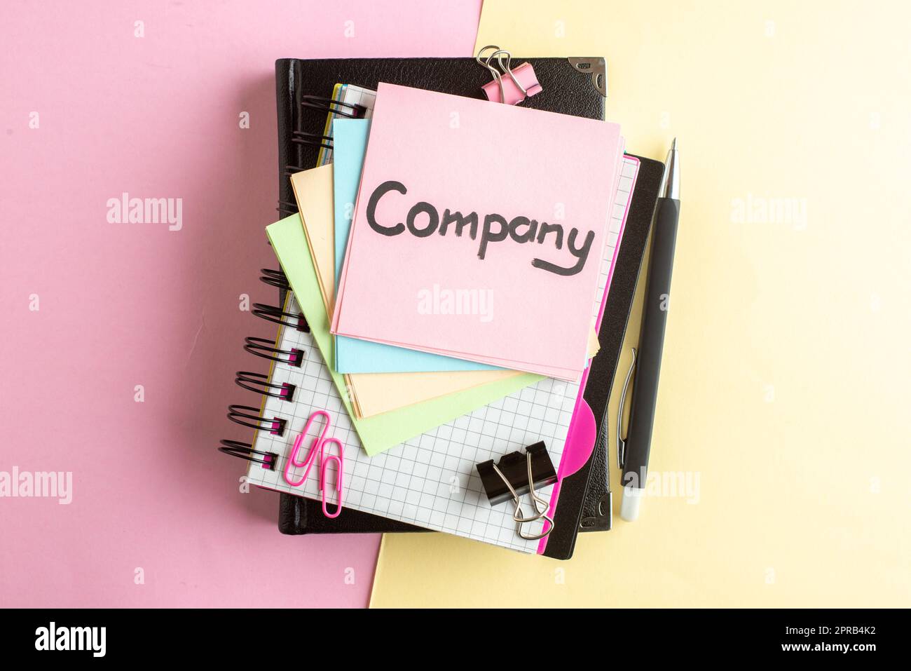 top view company written note with stickers on yellow-pink background ...