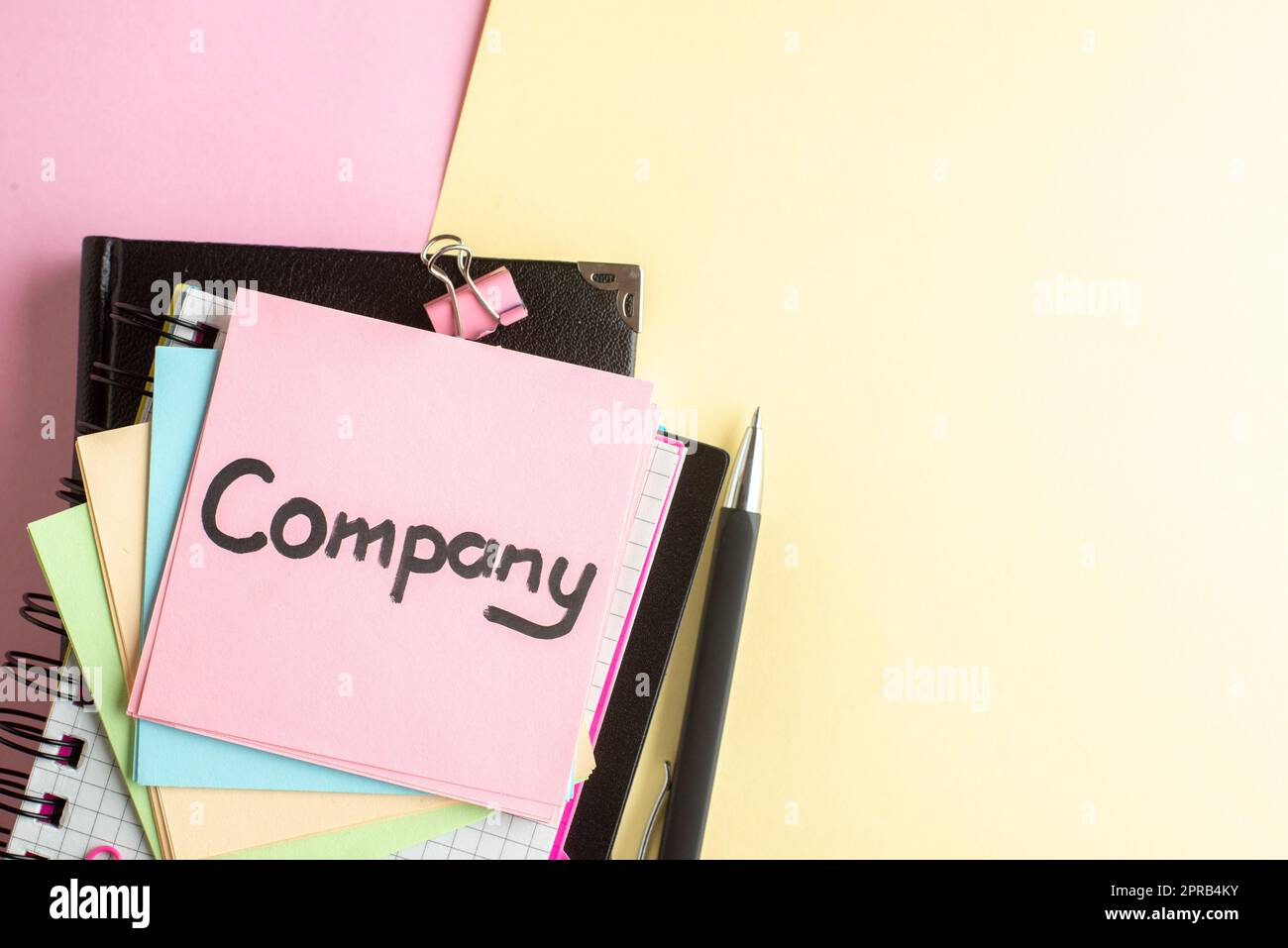 top view company written note with stickers on yellow-pink background ...