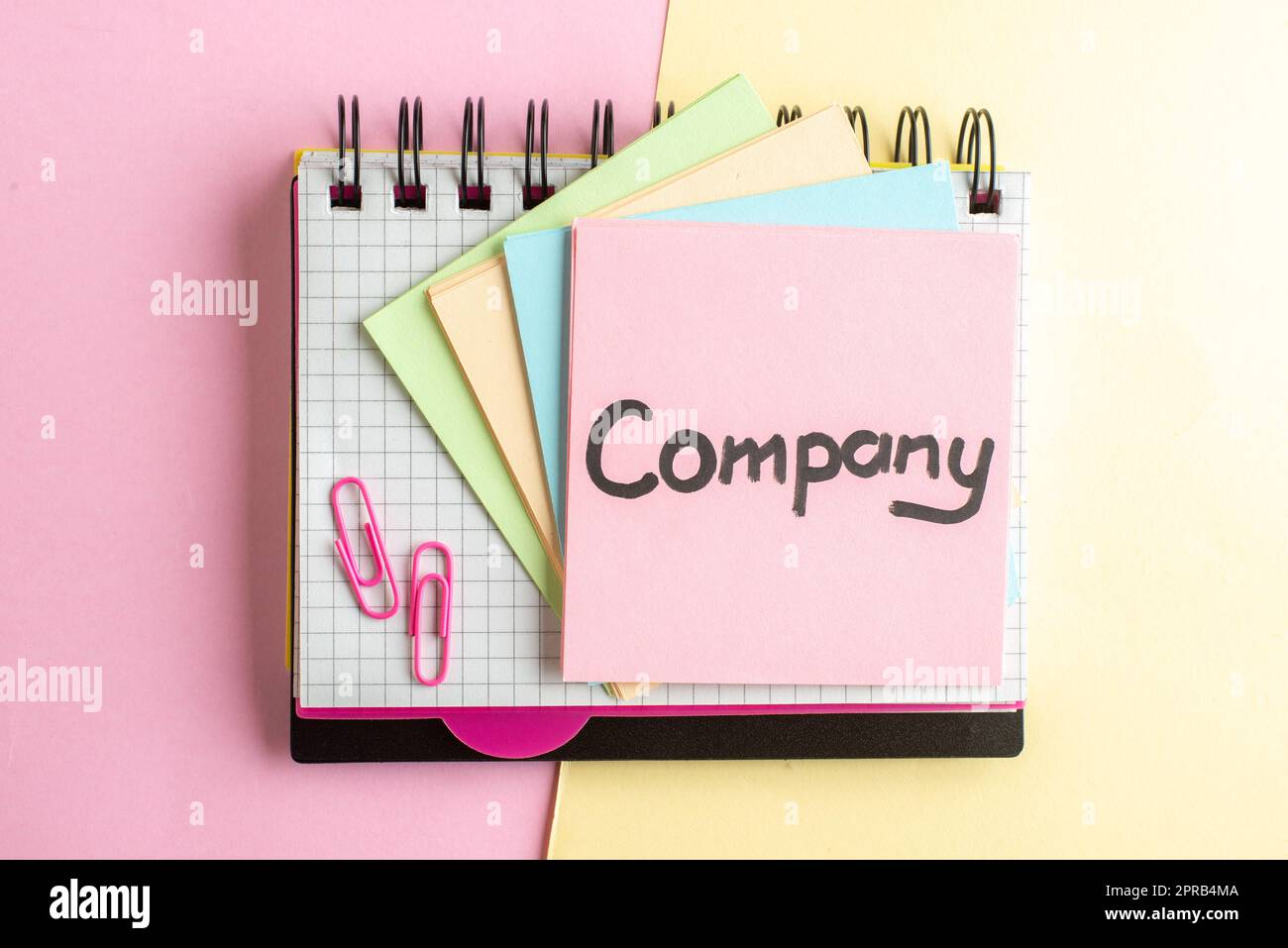 top view company written note with stickers on yellow-pink background ...