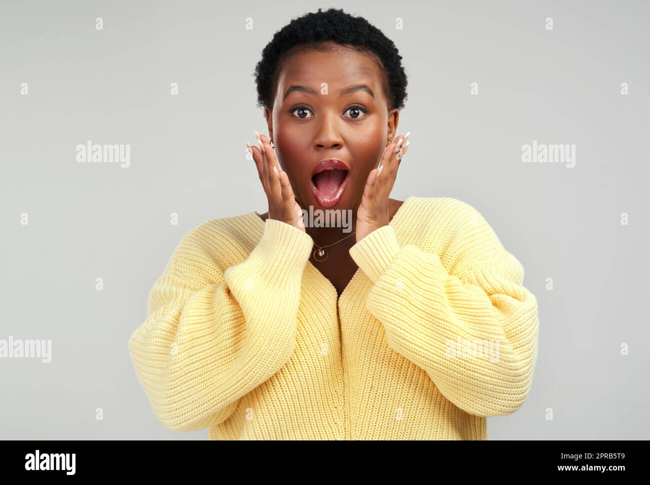 The secret is out. a young woman looking surprised while posing against ...