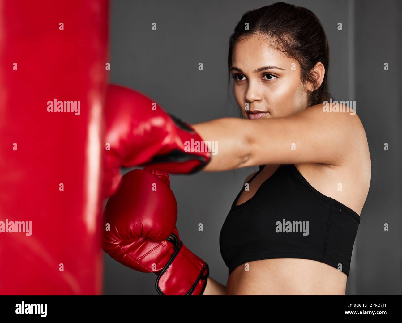 She packs a punch. an attractive young female boxer training in the gym ...