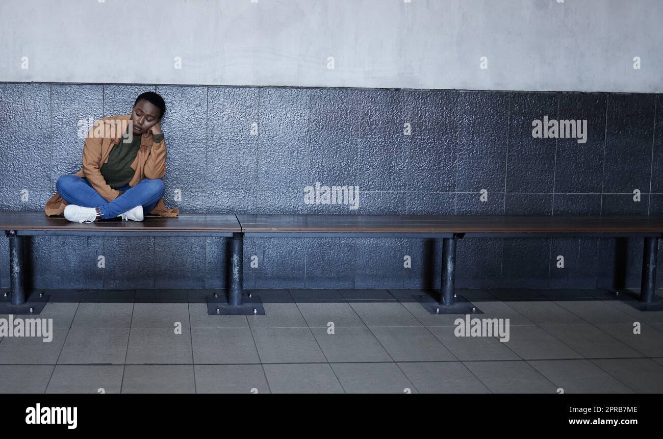 Shes thinking about running away. Full length shot of a young woman looking depressed while ...
