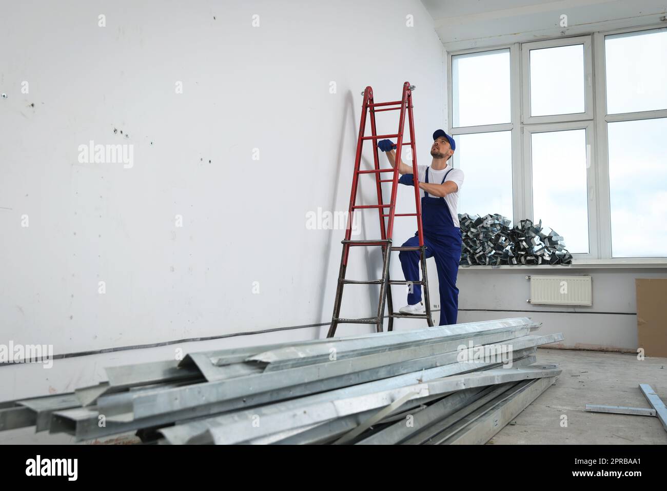 Construction worker climbing up stepladder in room prepared for ...