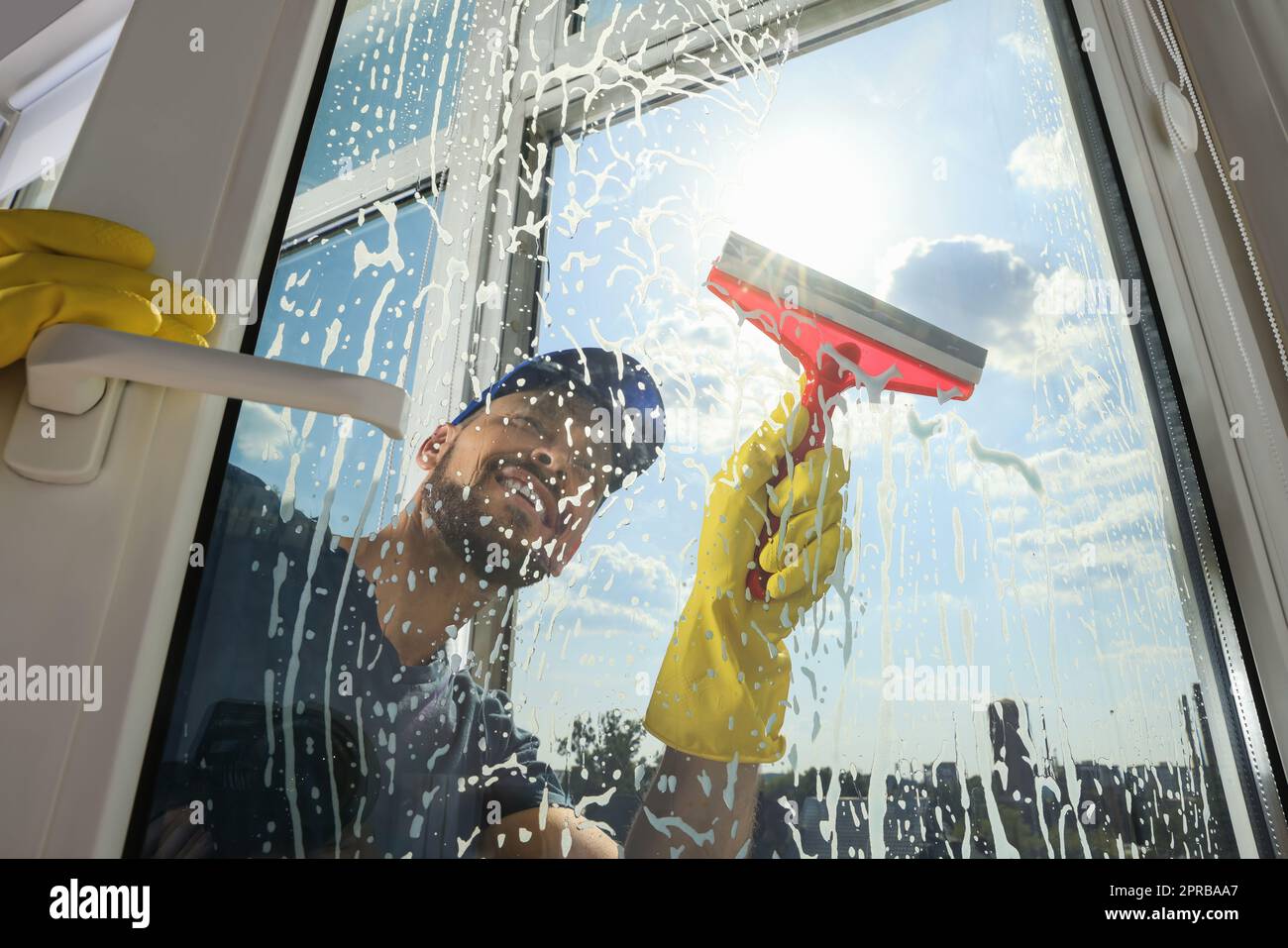 Man cleaning glass with squeegee indoors, low angle view Stock Photo ...