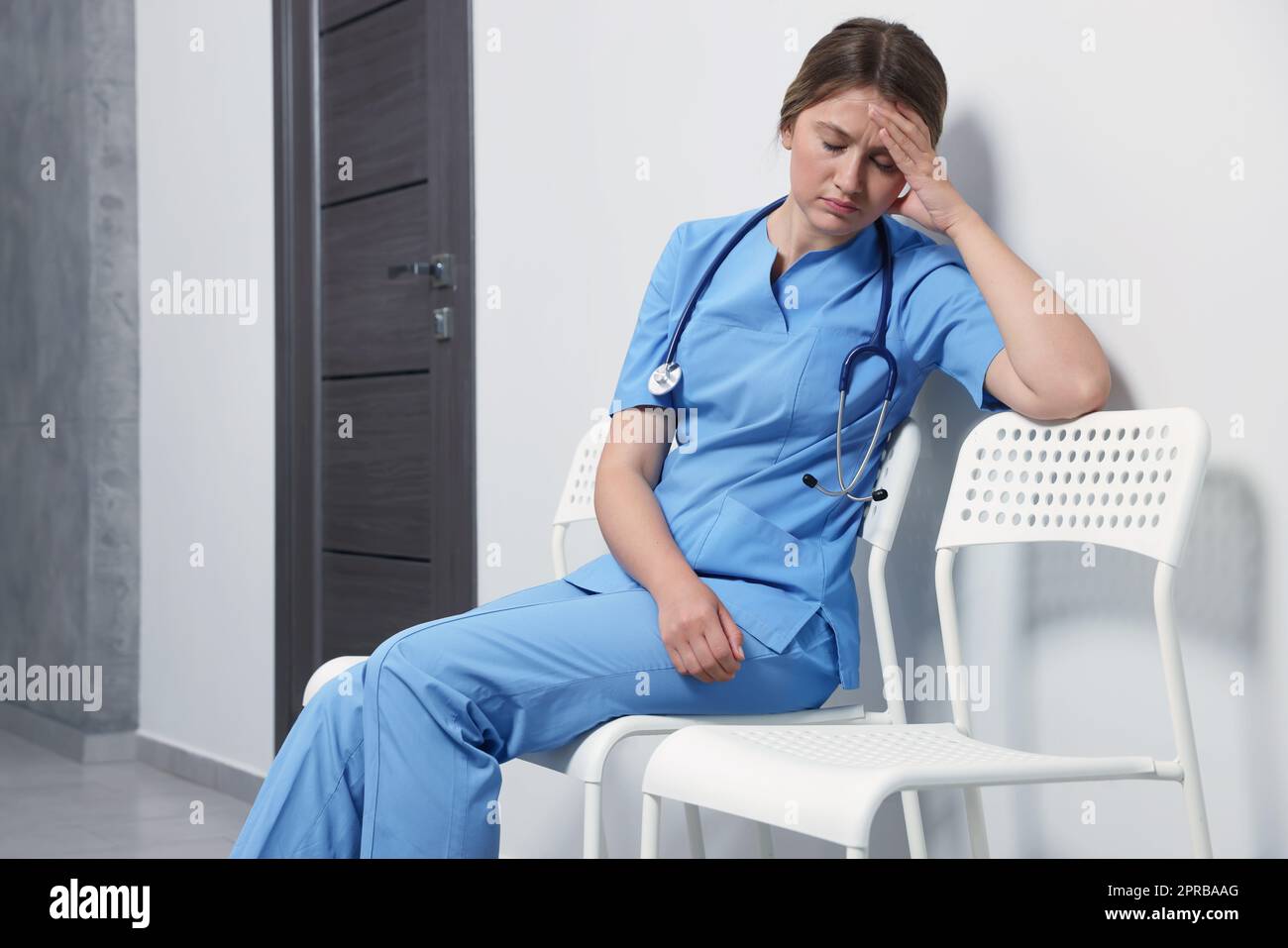 Exhausted doctor resting on chair in hospital Stock Photo - Alamy