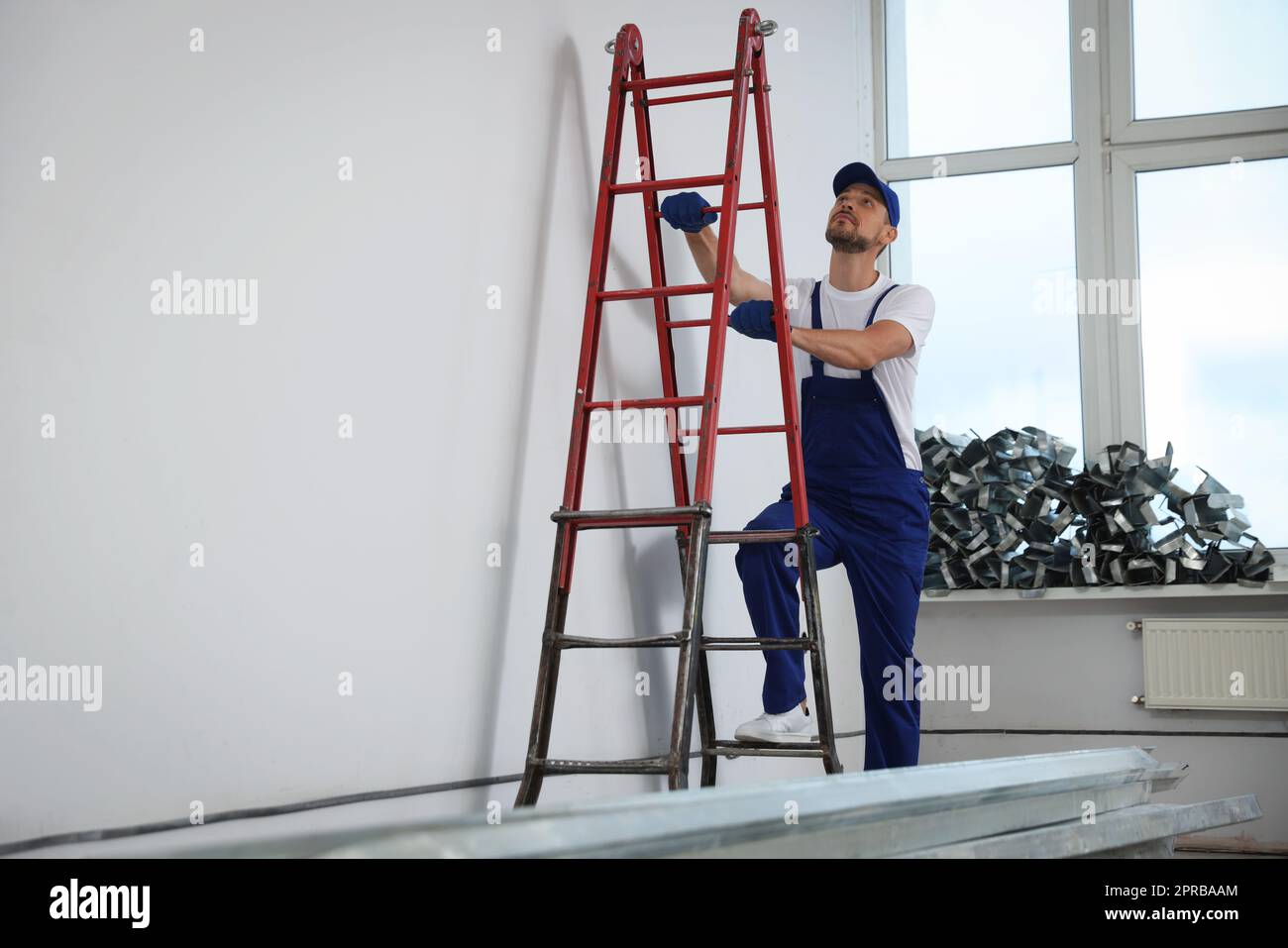 Construction worker climbing up stepladder in room prepared for ...