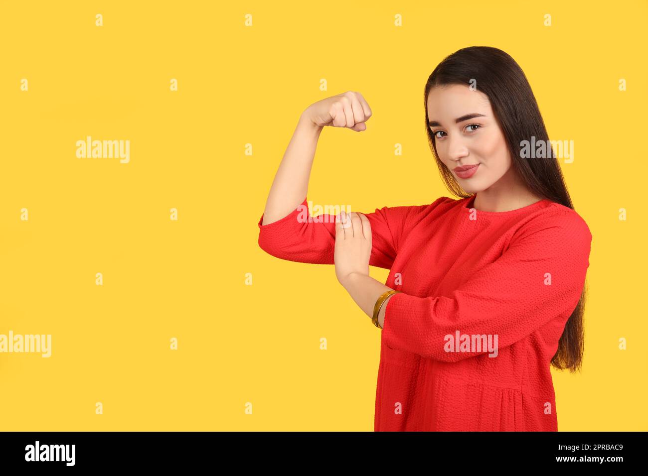 Strong woman as symbol of girl power on yellow background, space for ...