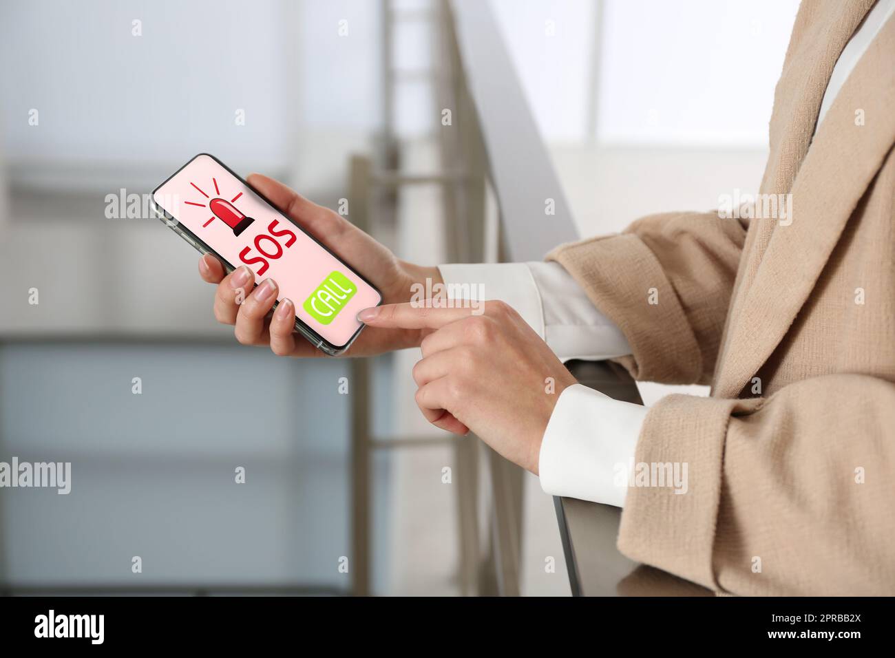 Woman holding smartphone with emergency call SOS on screen indoors ...