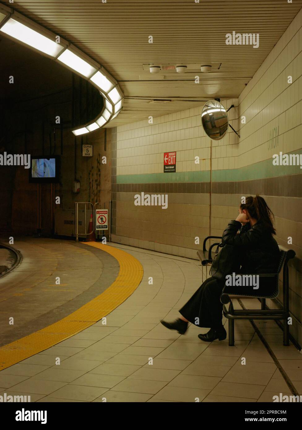A young woman wearing a denim jacket sitting and waiting for the train ...