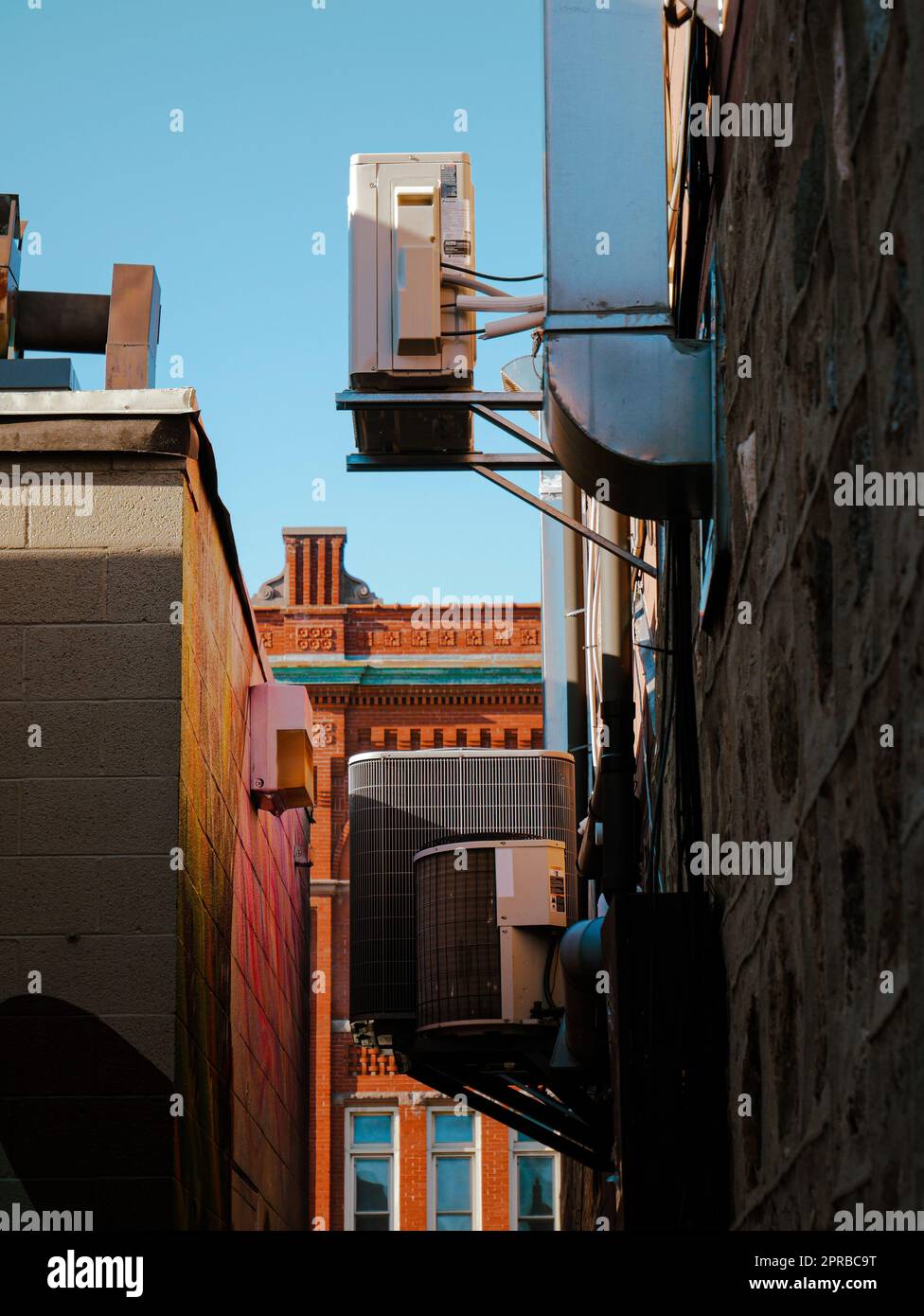 An outdoor air conditioning unit is visible in a narrow alleyway, with ...