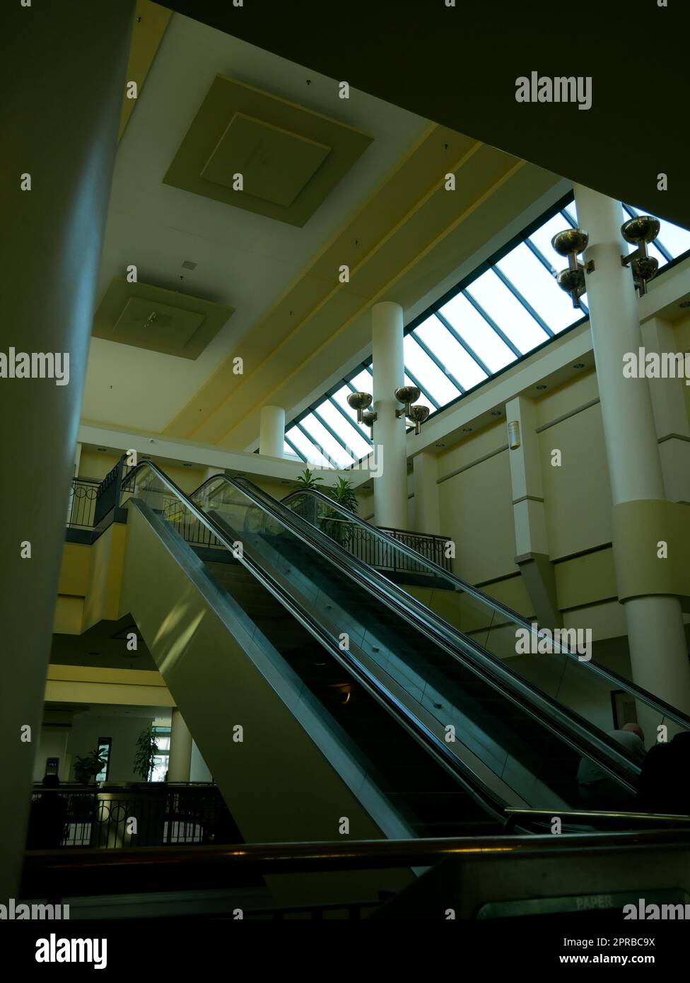 An illuminated escalator in a modern building, ascending to the next ...