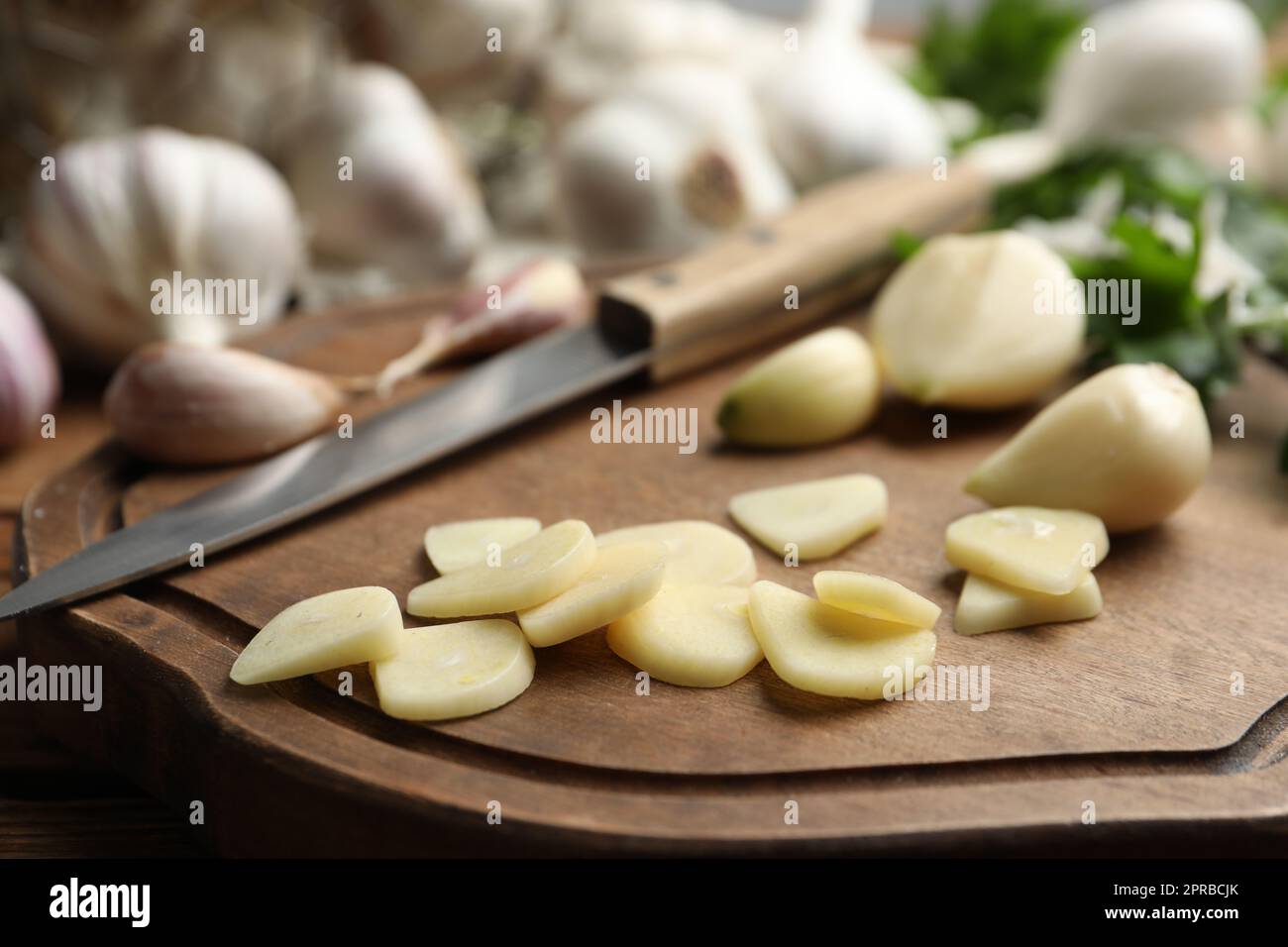 Fresh whole and cut garlic on wooden board, closeup. Organic product ...