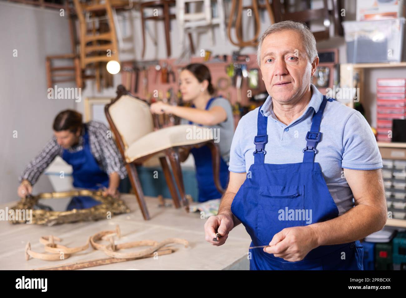 Master restoration worker dressed in overalls poses in working ...