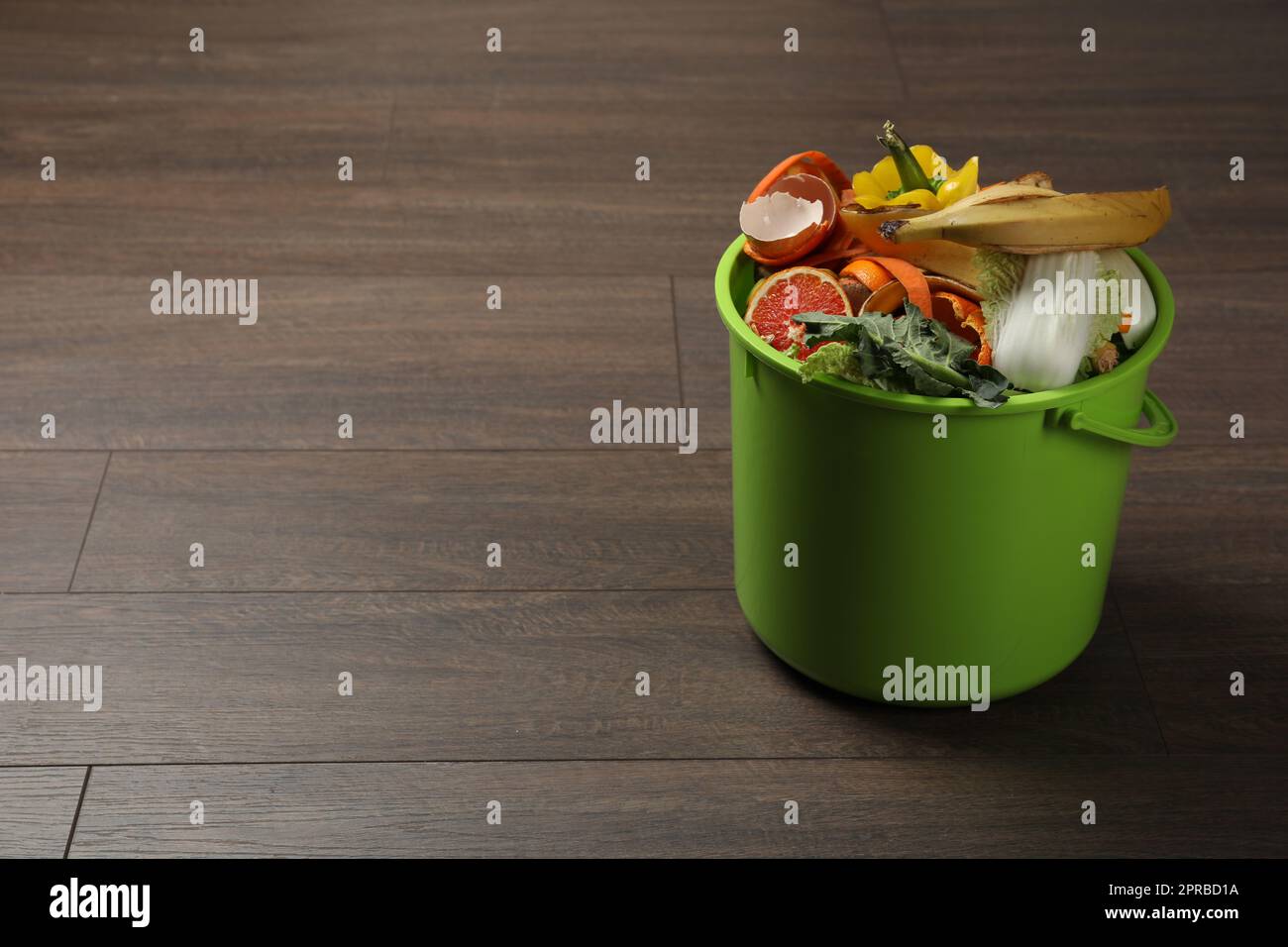 Trash bin with natural garbage on wooden background, space for text ...