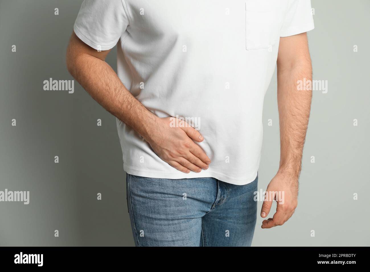 Man suffering from acute appendicitis on light grey background, closeup ...