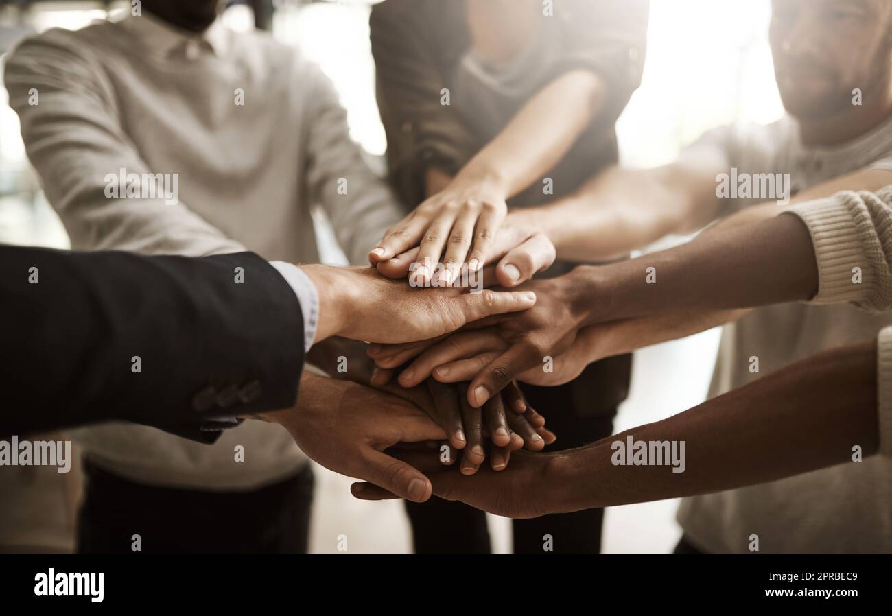 Businesspeople with their hands together in a huddle pile showing support, teamwork and close ...