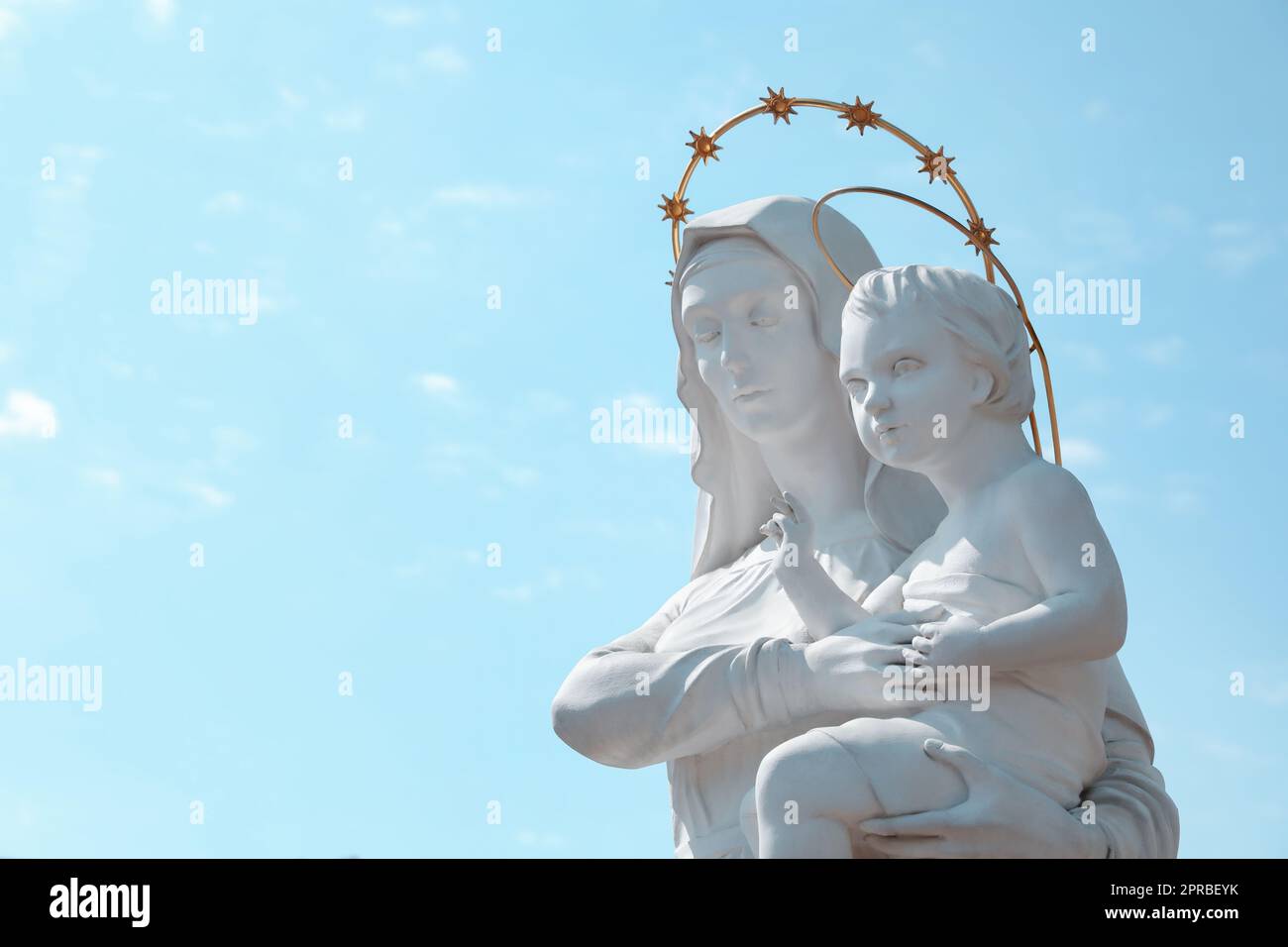 Beautiful statue of Virgin Mary and baby Jesus against blue sky. Space ...
