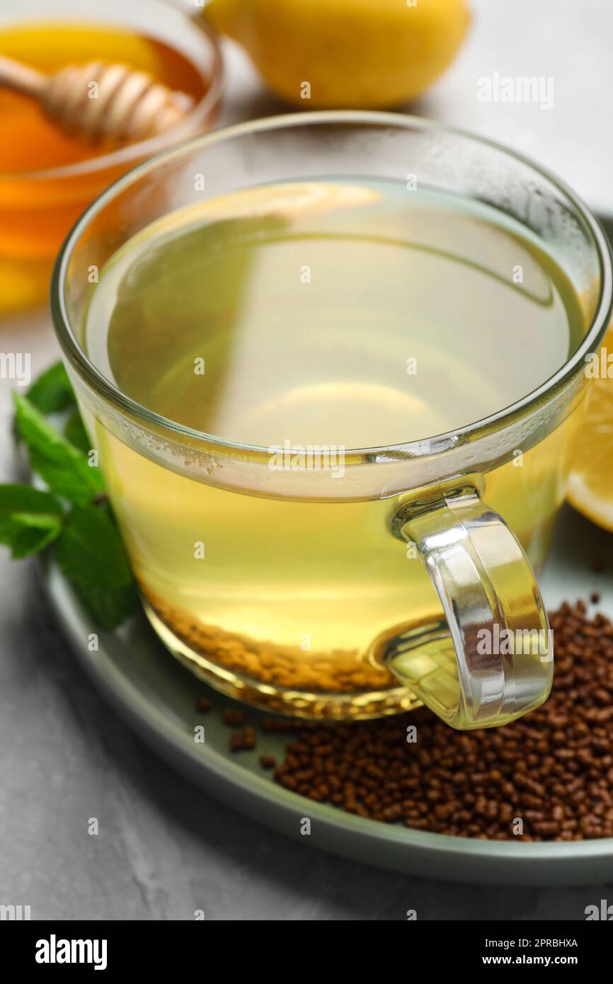 Cup of aromatic buckwheat tea, mint and granules on light grey marble ...