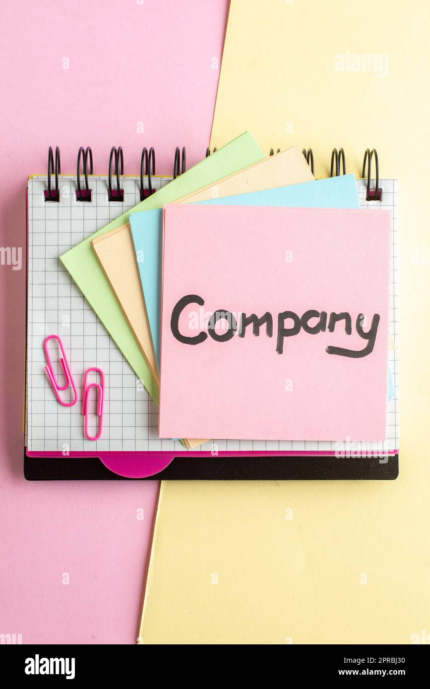 top view company written note with stickers on yellow-pink background ...