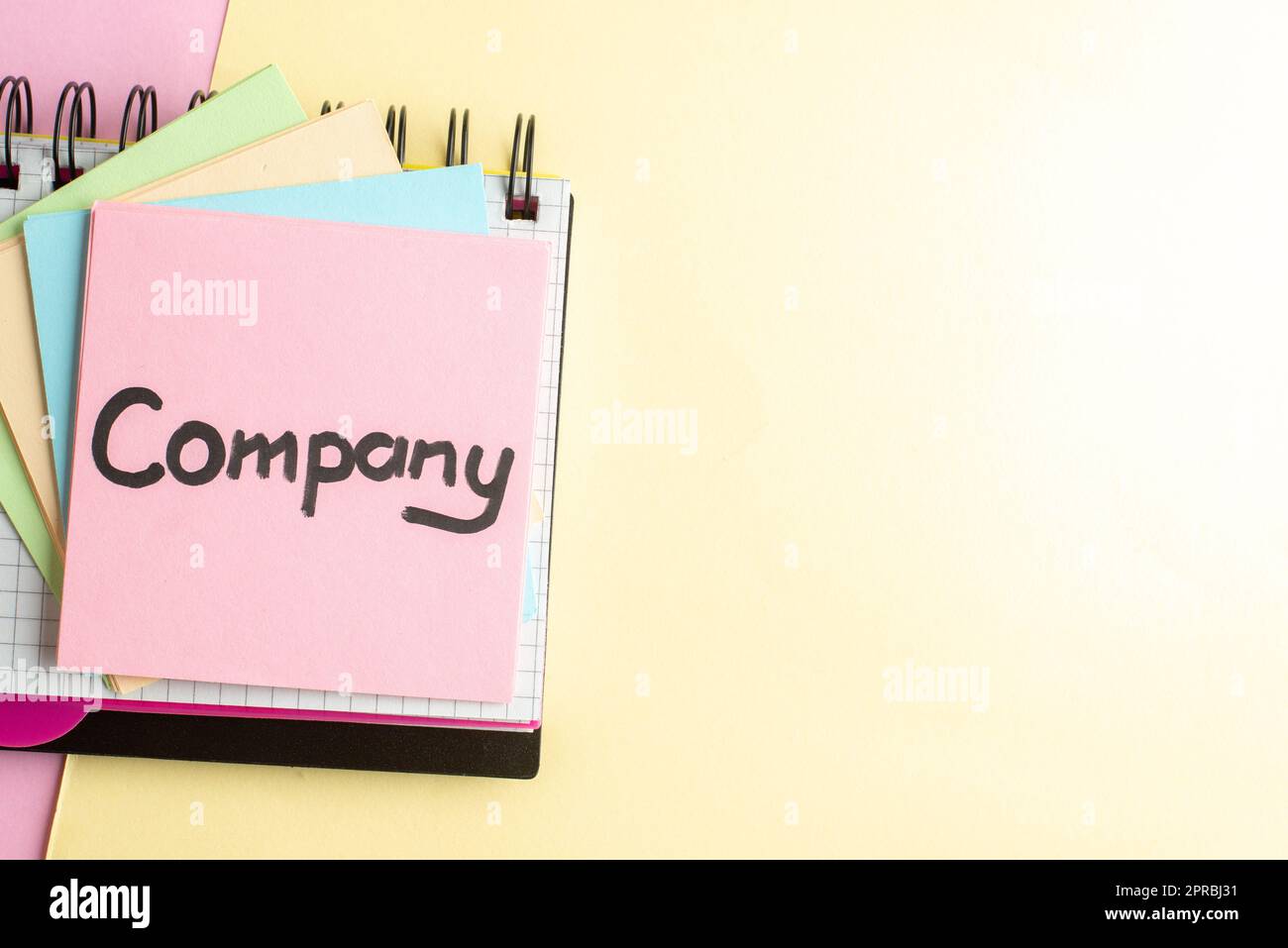 top view company written note with stickers on yellow-pink background ...