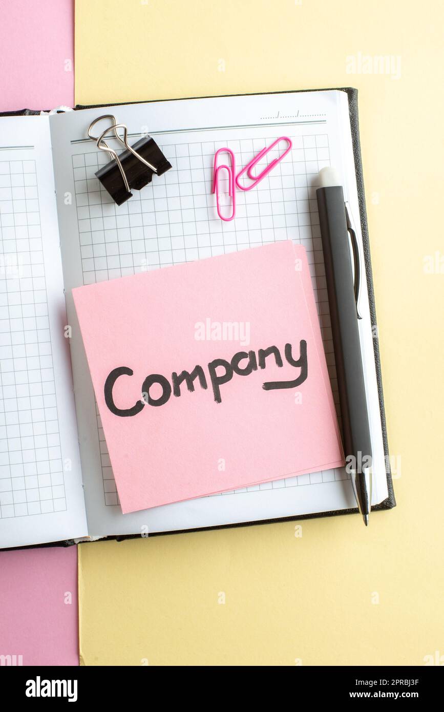 top view company written note on pink sticker with notepad yellow-pink ...