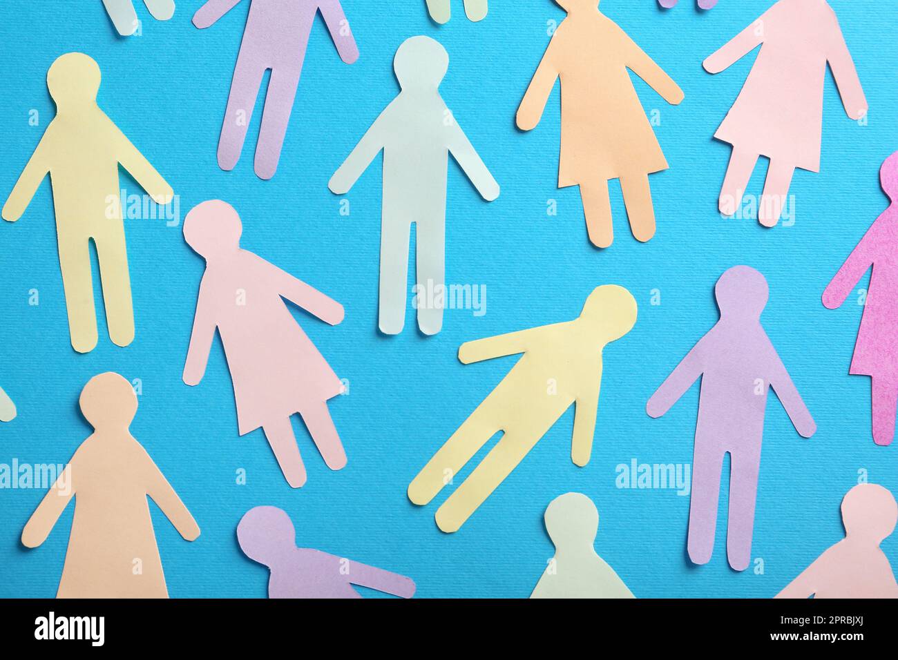 Many different paper human figures on light blue background, flat lay ...