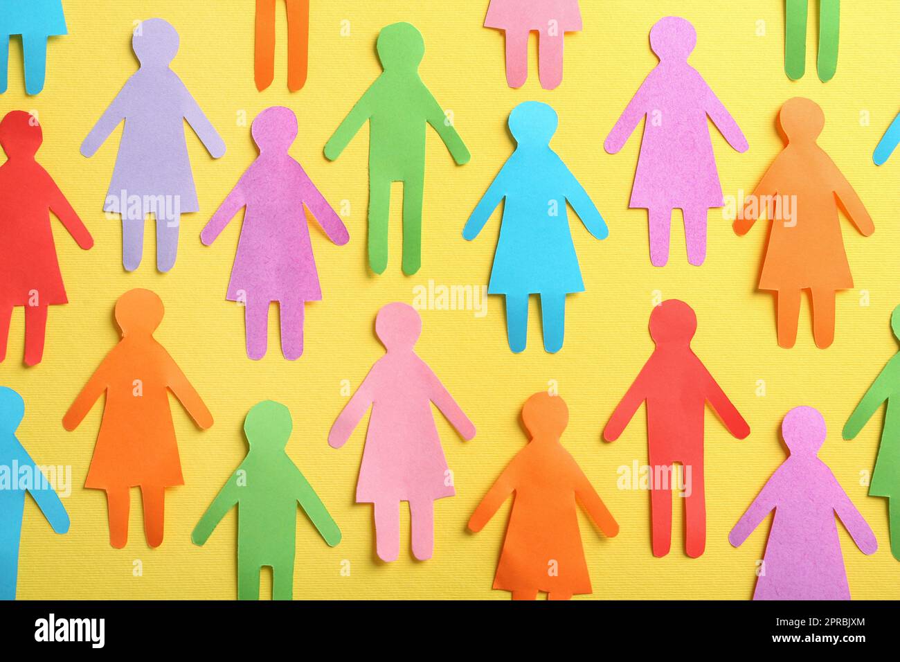 Many different paper human figures on yellow background, flat lay ...
