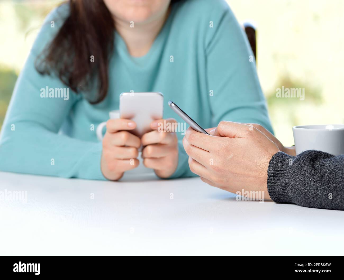 Two friends using their smart phones in a bar Stock Photo - Alamy