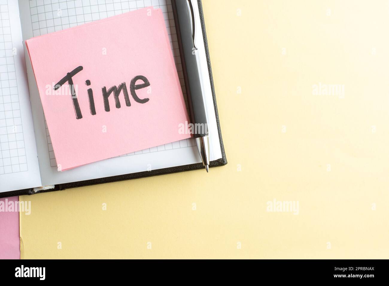 top view time written note on pink sticker with notepad yellow-pink ...