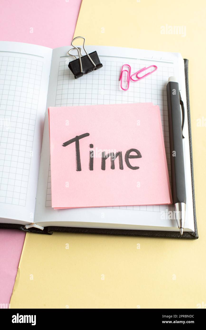 top view time written note on pink sticker with notepad yellow-pink ...