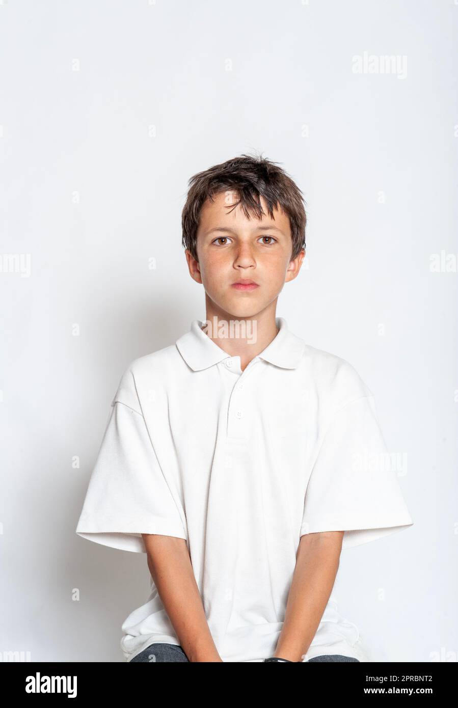 Young boy against a white background looking straight at camera ...