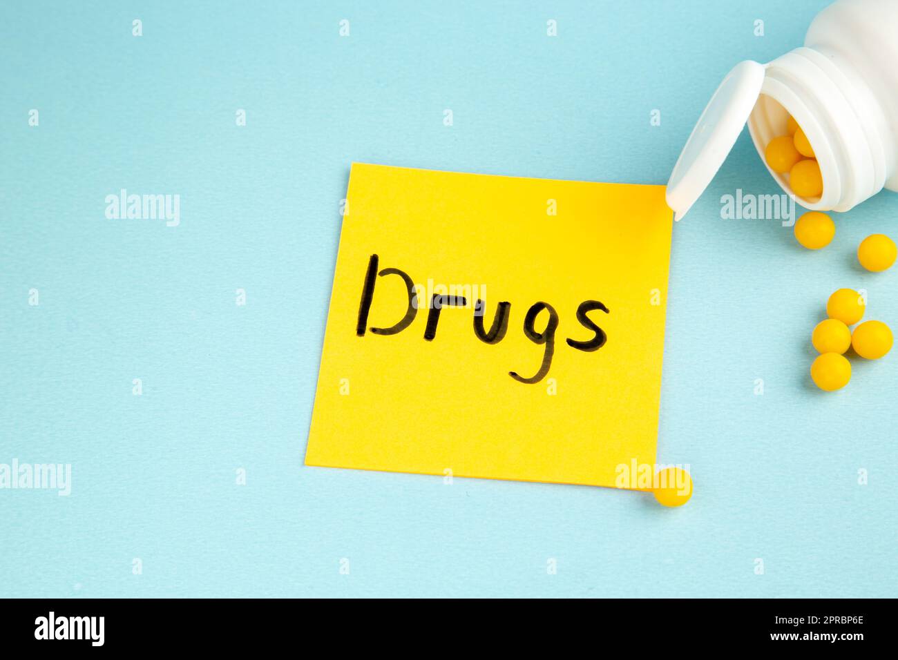 top view yellow pills with drugs written note on blue background color ...