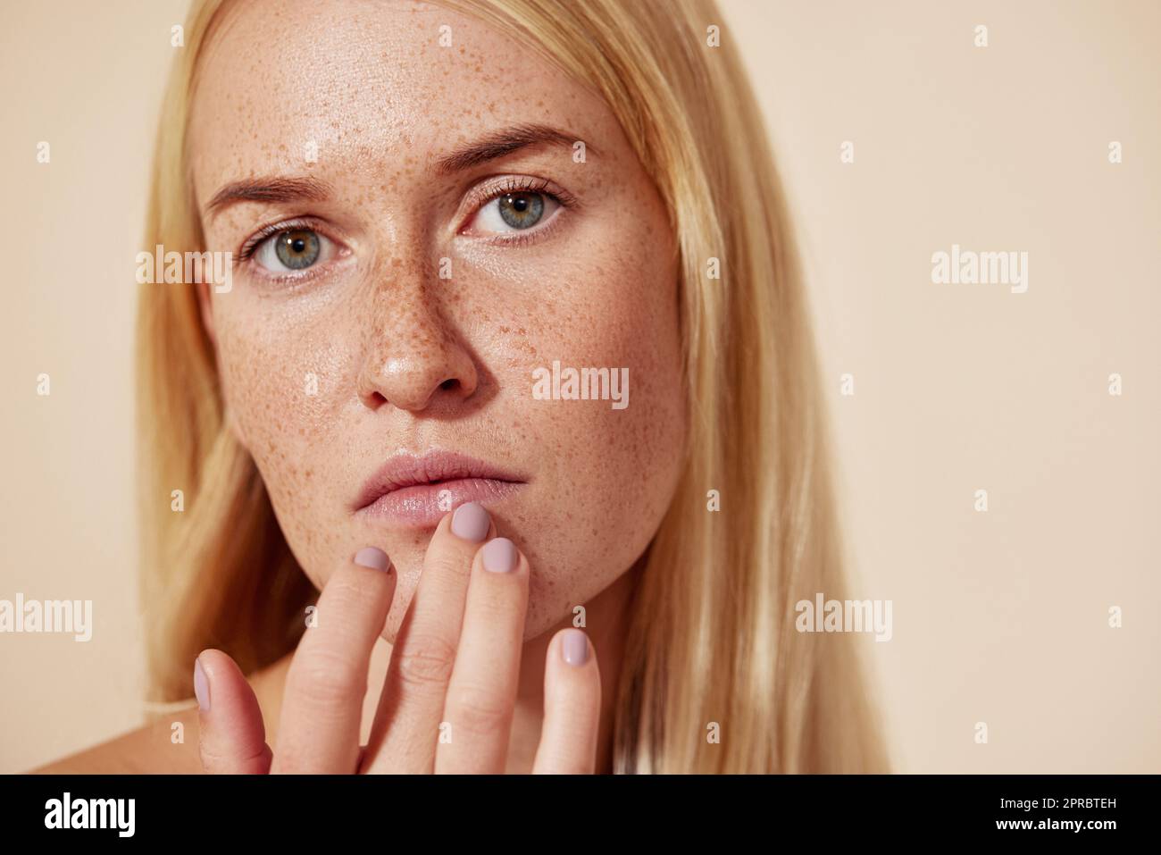 Close up of a woman with freckles touching her lip with a finger. Young ...