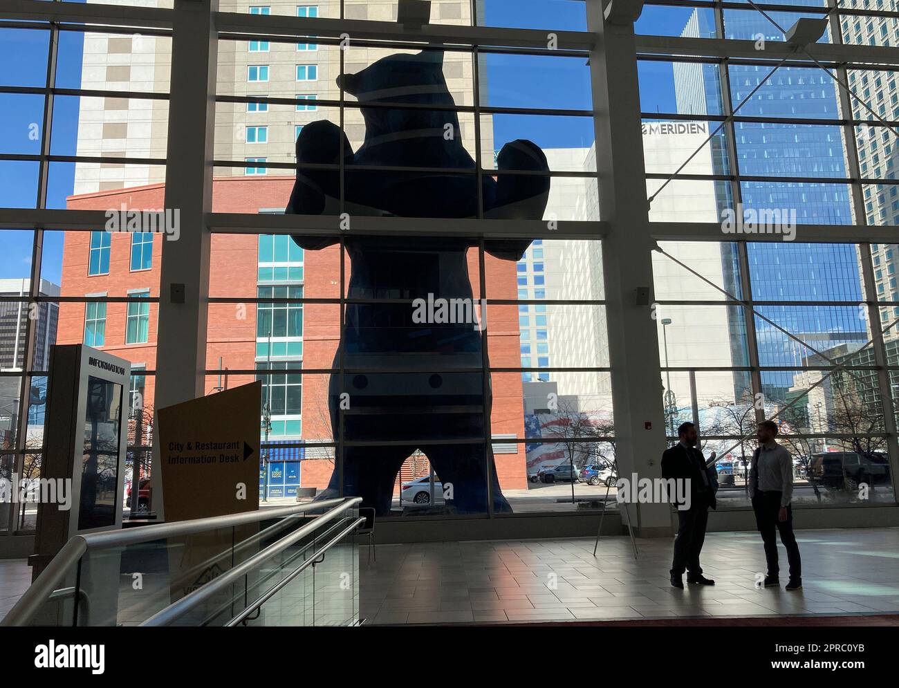 The Big Blue Bear sculpture is silhouetted as it looks in the window of ...