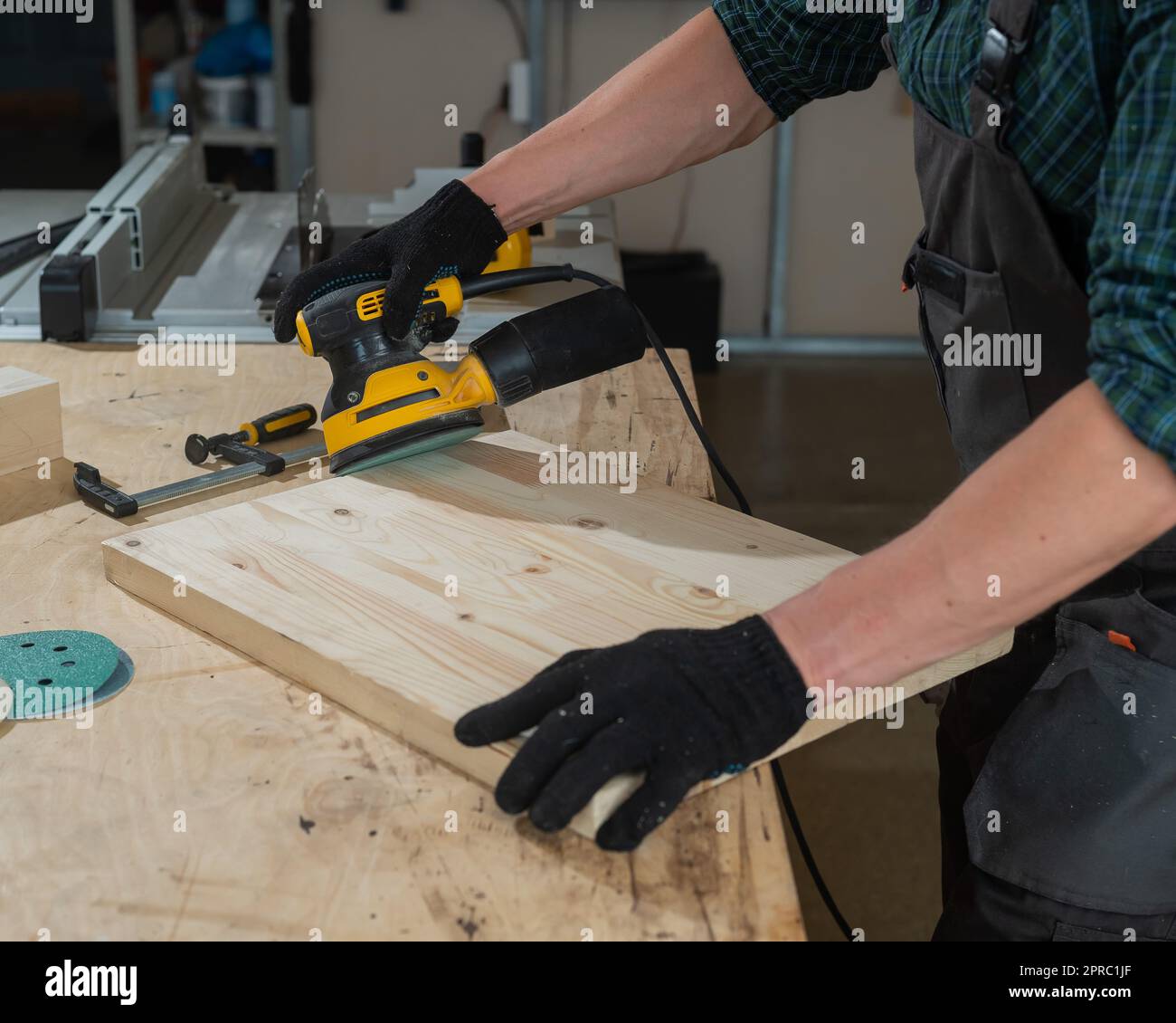 A man using an orbital wood sander in a workshop. Close-up of a ...