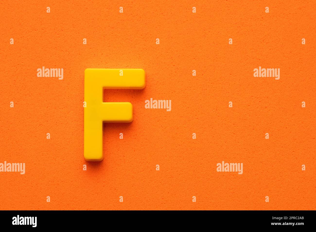 Yellow plastic letter D uppercase on orange foamy background Stock ...