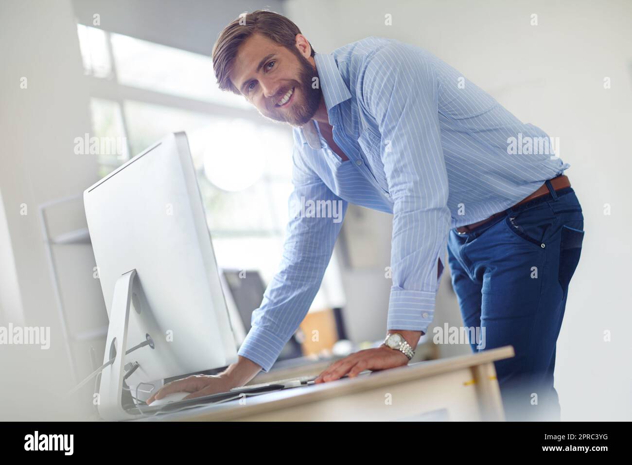 Success is just a click away. a designer leaning towards his computer ...
