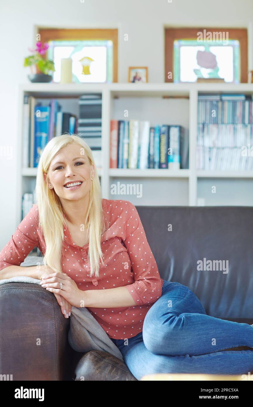 Portrait of a young joyful blonde woman relaxing at home on the sofa ...