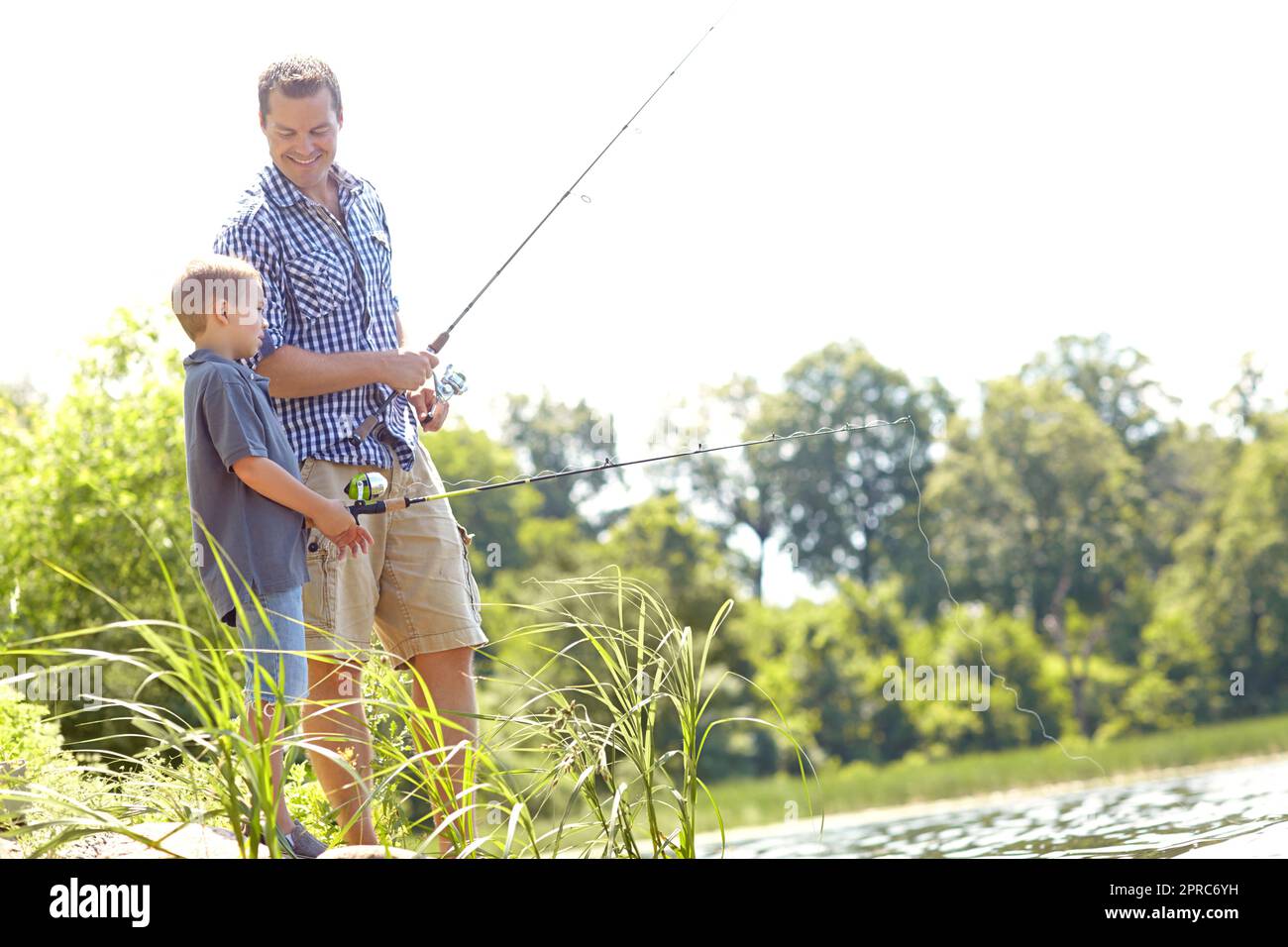 Teaching my son how to catch a fish. Father and son standing beside a ...
