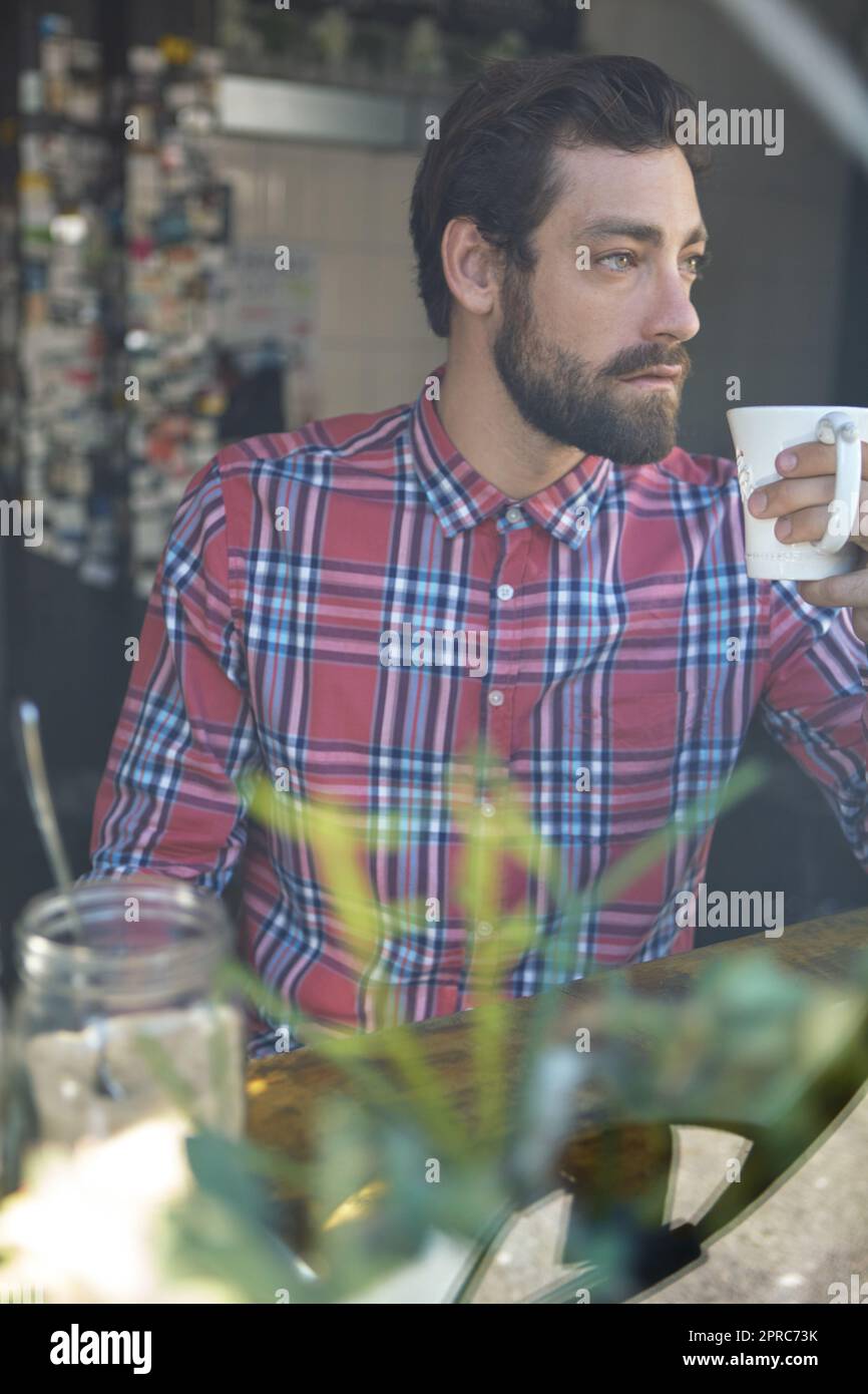 Collecting his thoughts over coffee. a young man drinking coffee in a ...