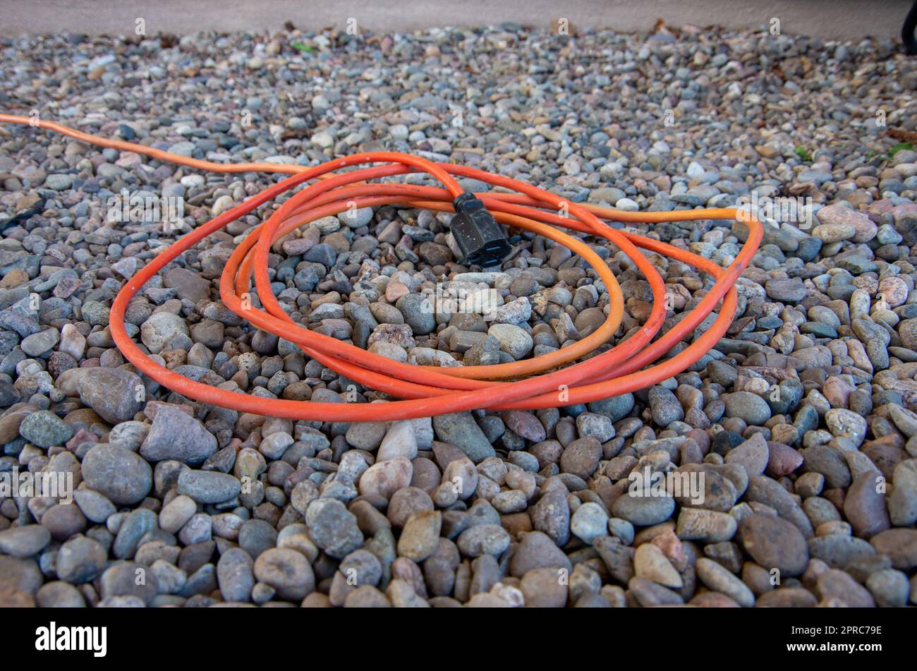 Orange Outdoor Extension Cord Sitting in Rock Bed Stock Photo - Alamy