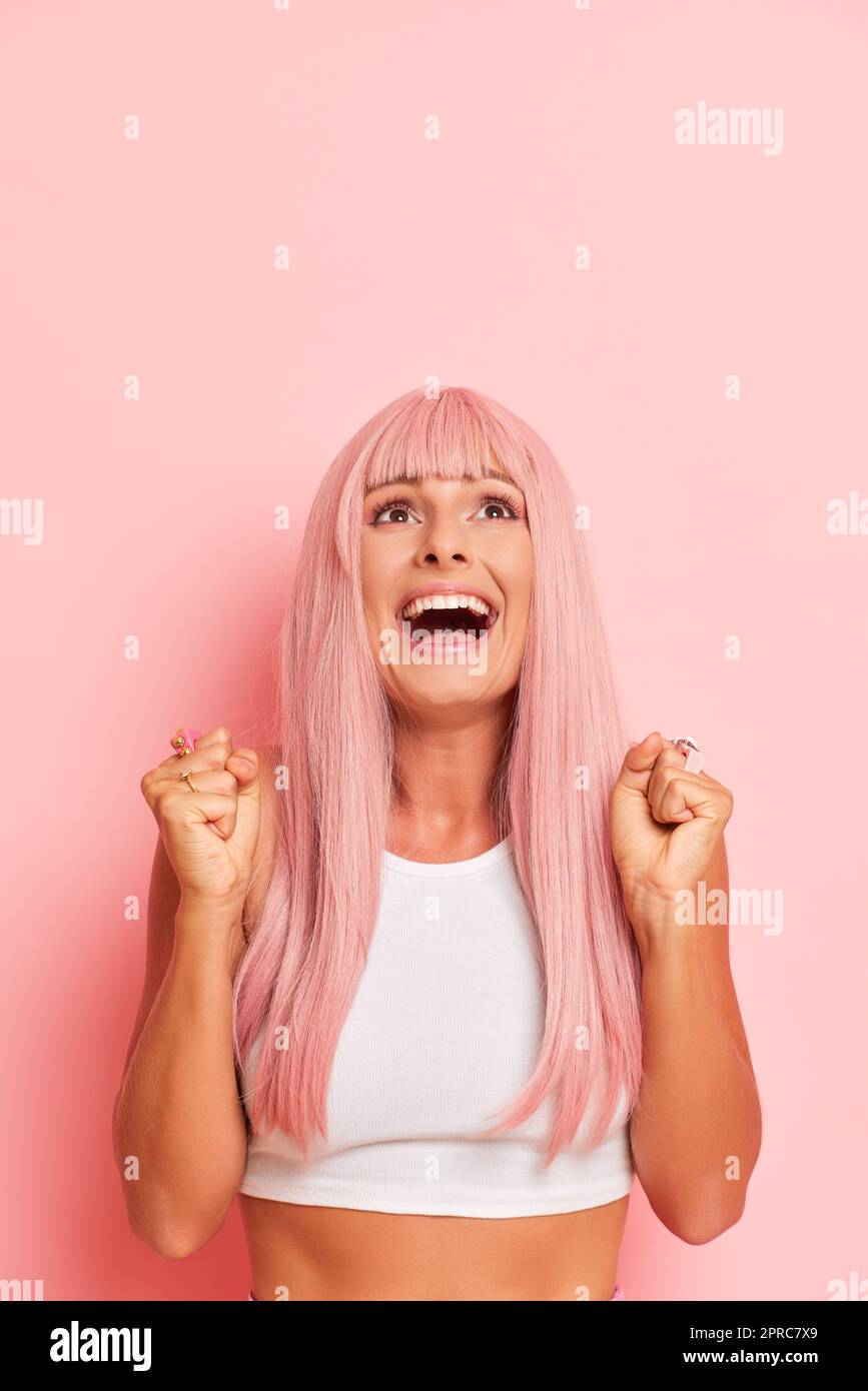 Portrait of excited beautiful pink-haired girl, holds fists up with ...
